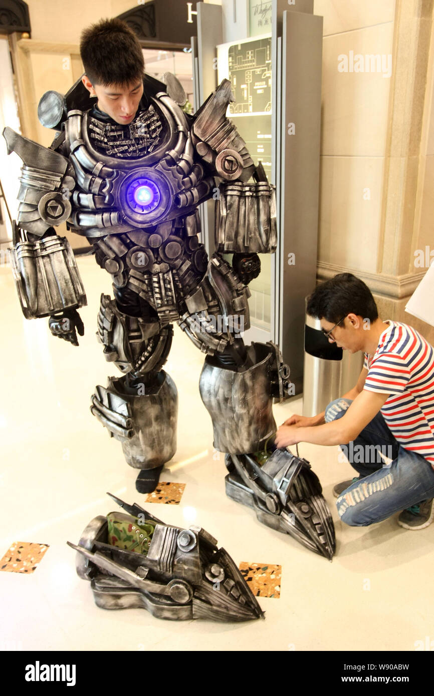 A staff member helps a performer put on his Transformers costume during ...