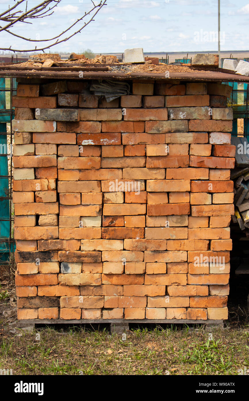 A pile of red bricks neatly folded on pallets. A lot of brick for ...
