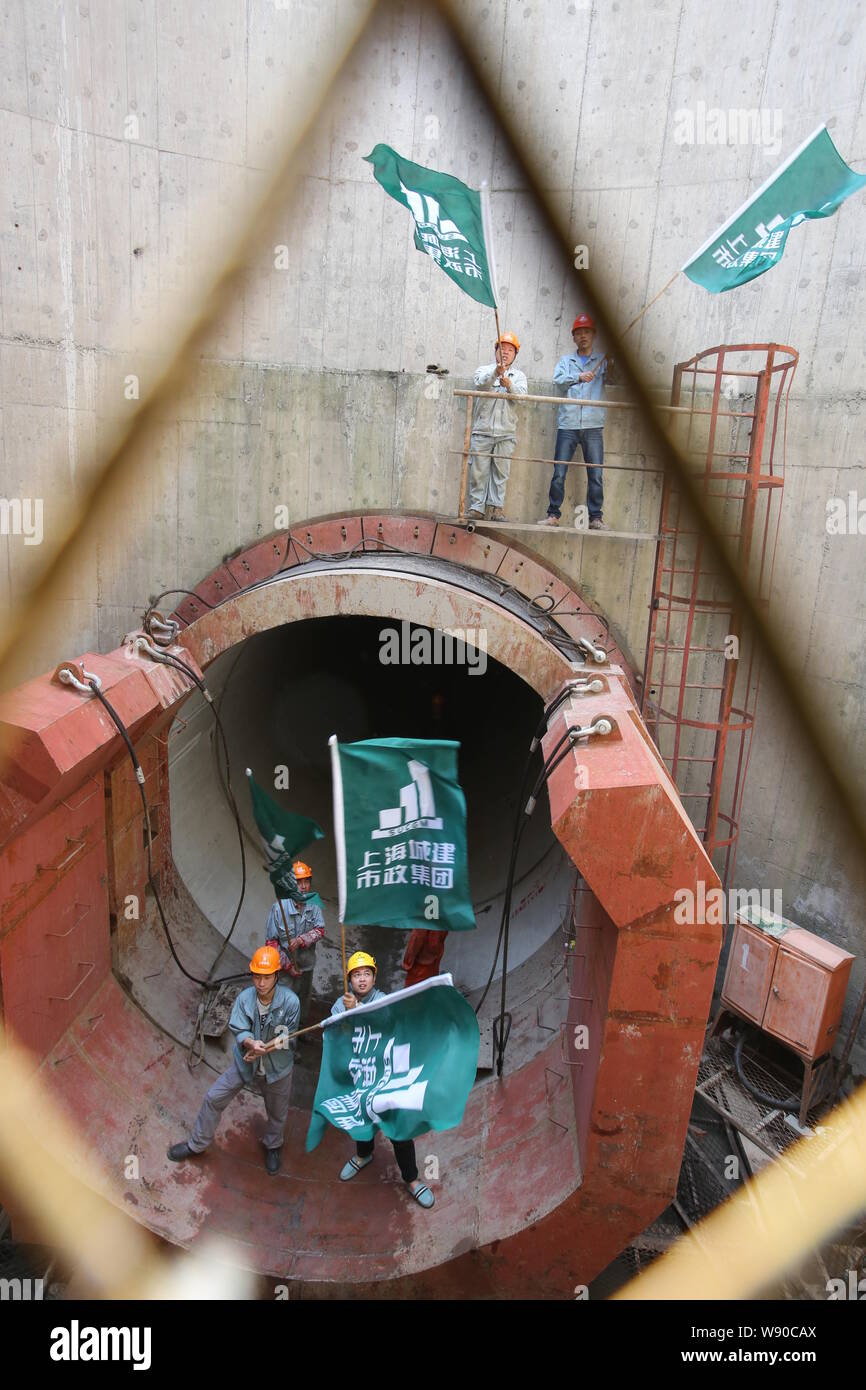 Workers wave flags as they succeed in laying a 4.64-meter sewage pipe ...