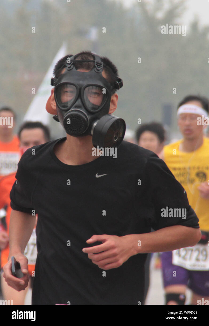 A Chinese participant wearing a gas mask runs during the 2014 Beijing ...