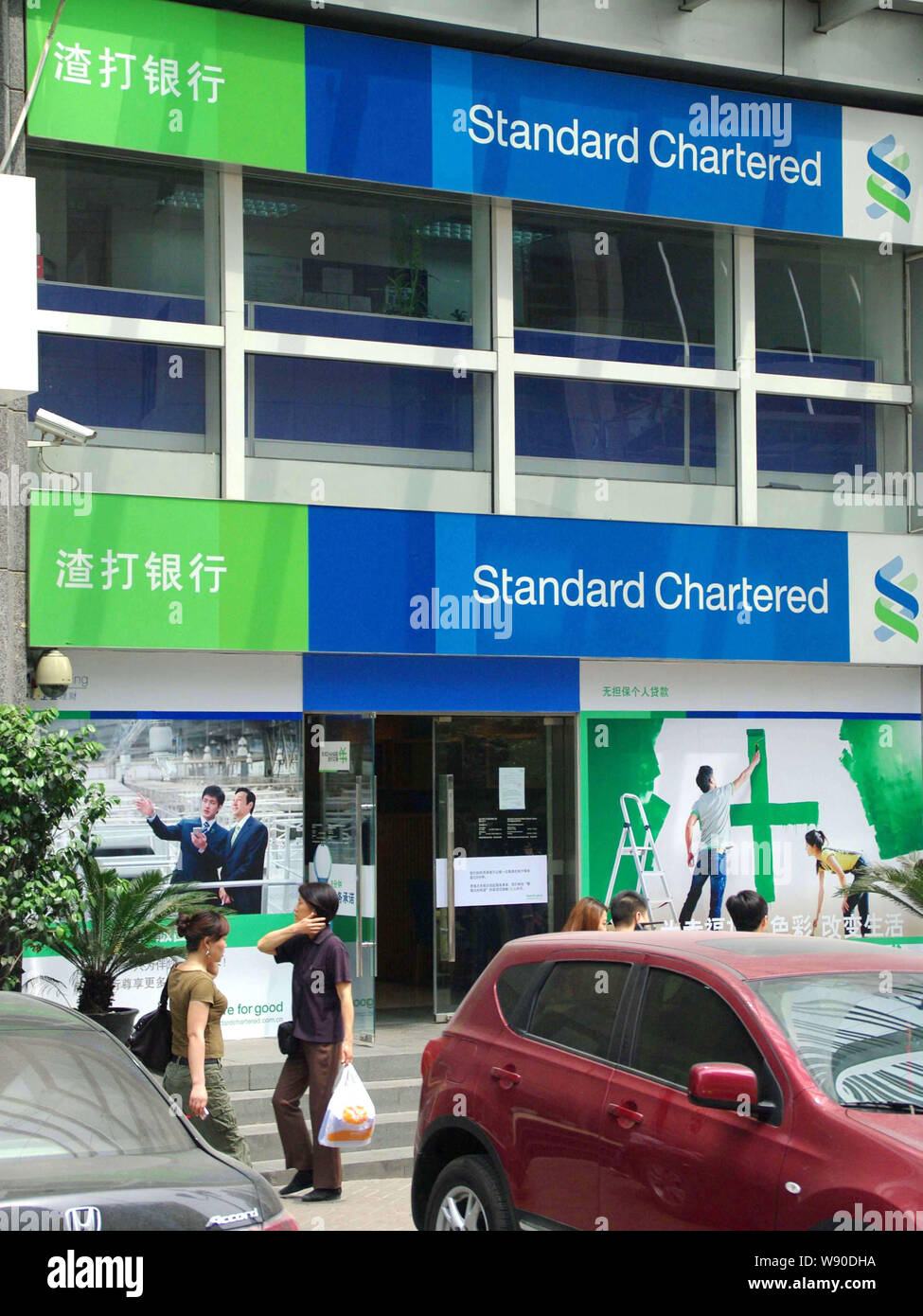 --FILE--Pedestrians walk past a branch of Standard Chartered Bank in ...