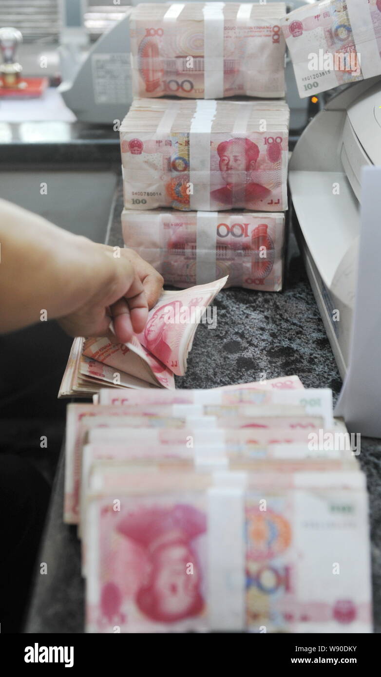 A Chinese clerk counts RMB (renminbi) yuan banknotes at a branch of the ...