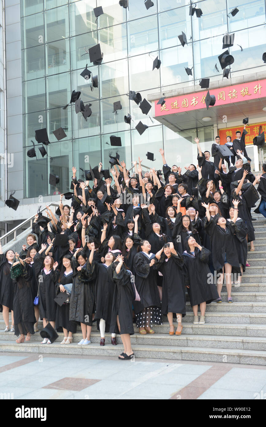 --FILE--Chinese graduates dressed in academic gowns throw hats into the ...