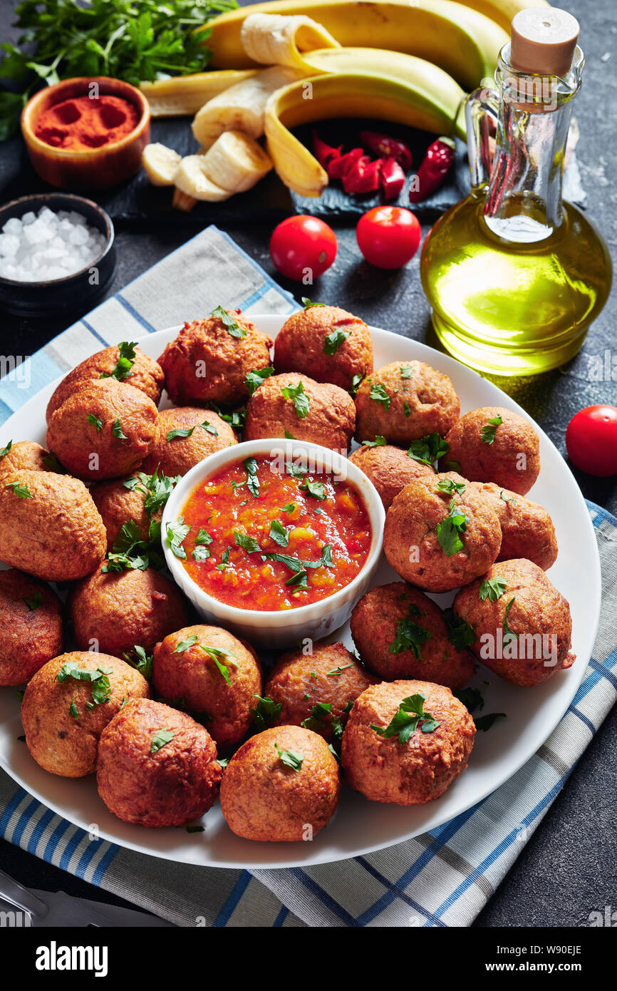 deep fried Plantain fritters Klako on a white plate with hot sauce ...
