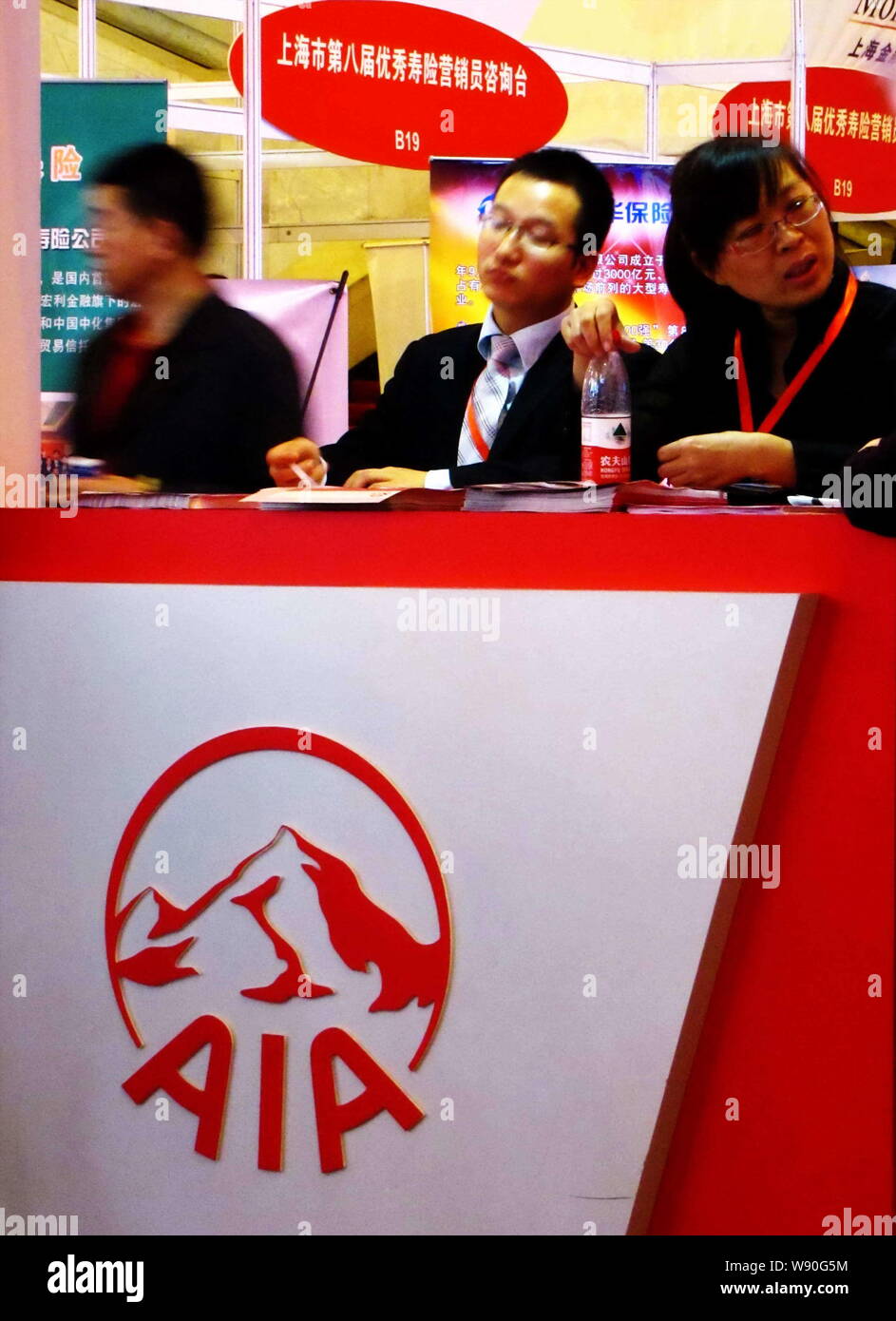 --FILE--Chinese employees work at the stand of AIA during an exhibition ...