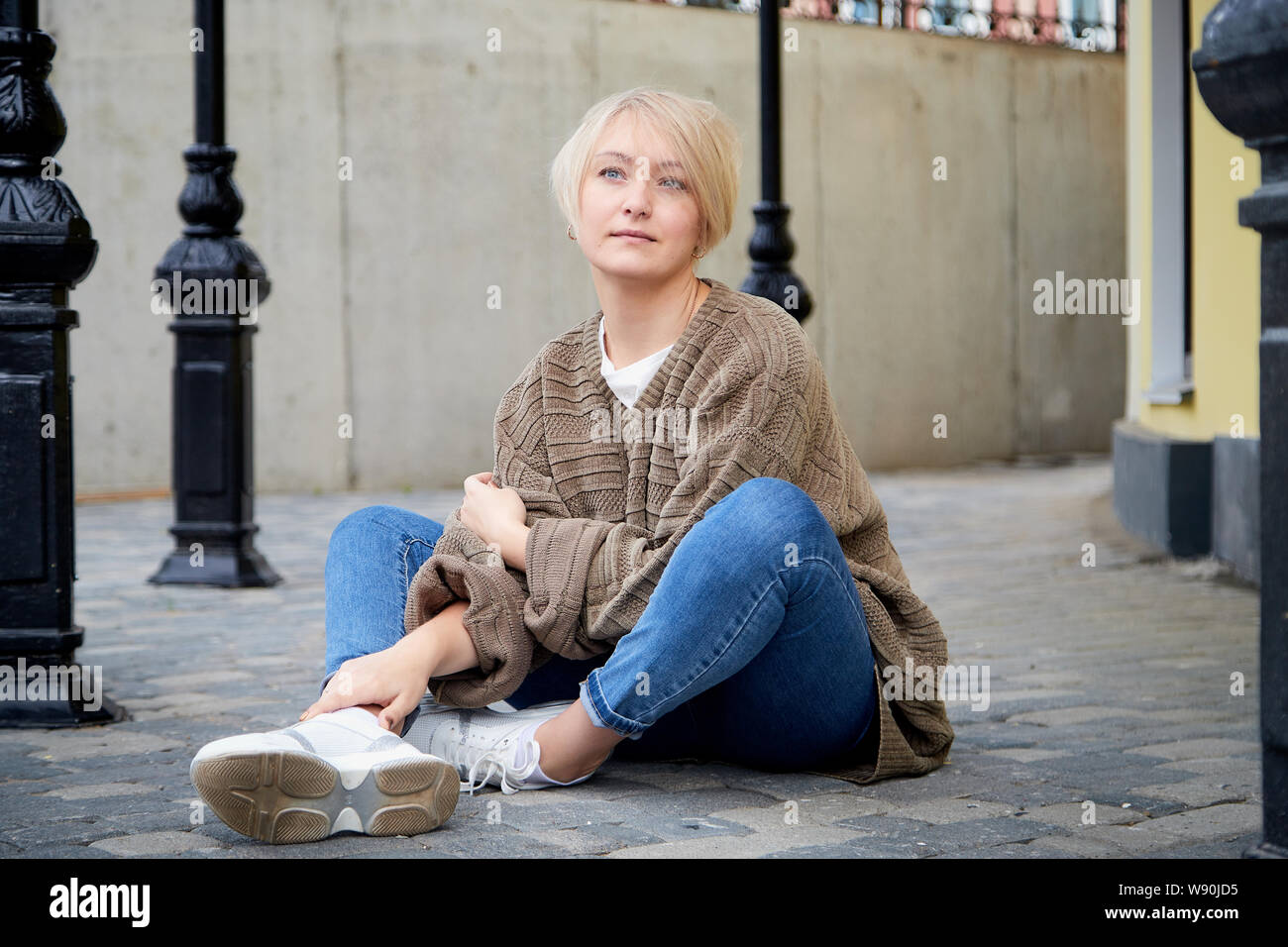 Blonde funny pretty girl on pavement in Central part of ancient city ...