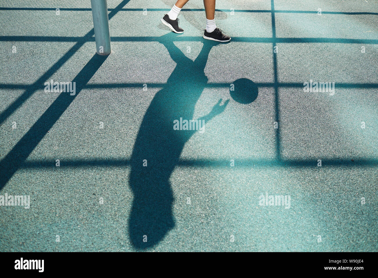 Shadow of unrecognizable man playing basketball in outdoor court ...