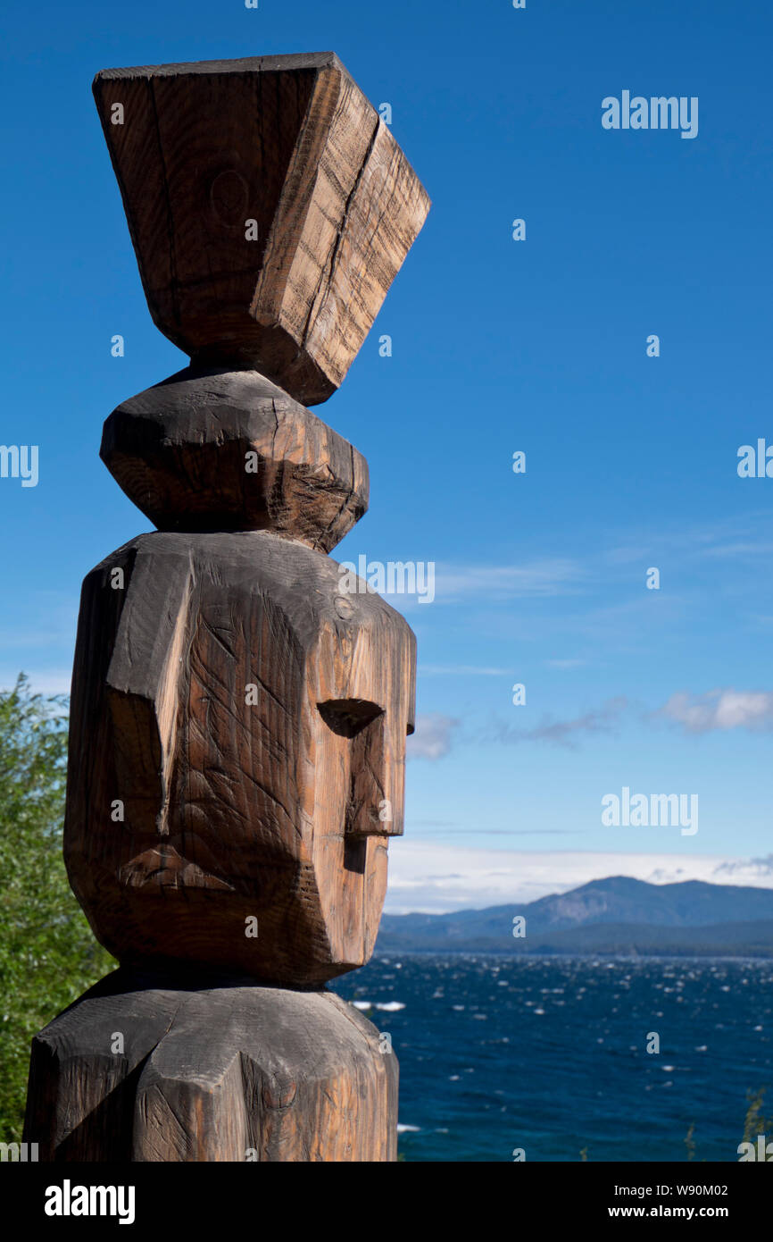 Wooden totem statues and views of Andes mountains by lake Nahuel Huapi ...