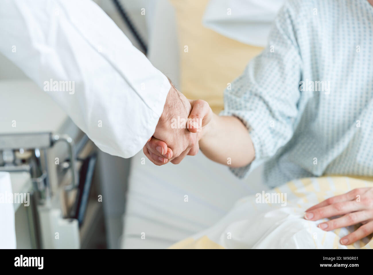 Doctor shaking hand of patient in hospital bed Stock Photo - Alamy