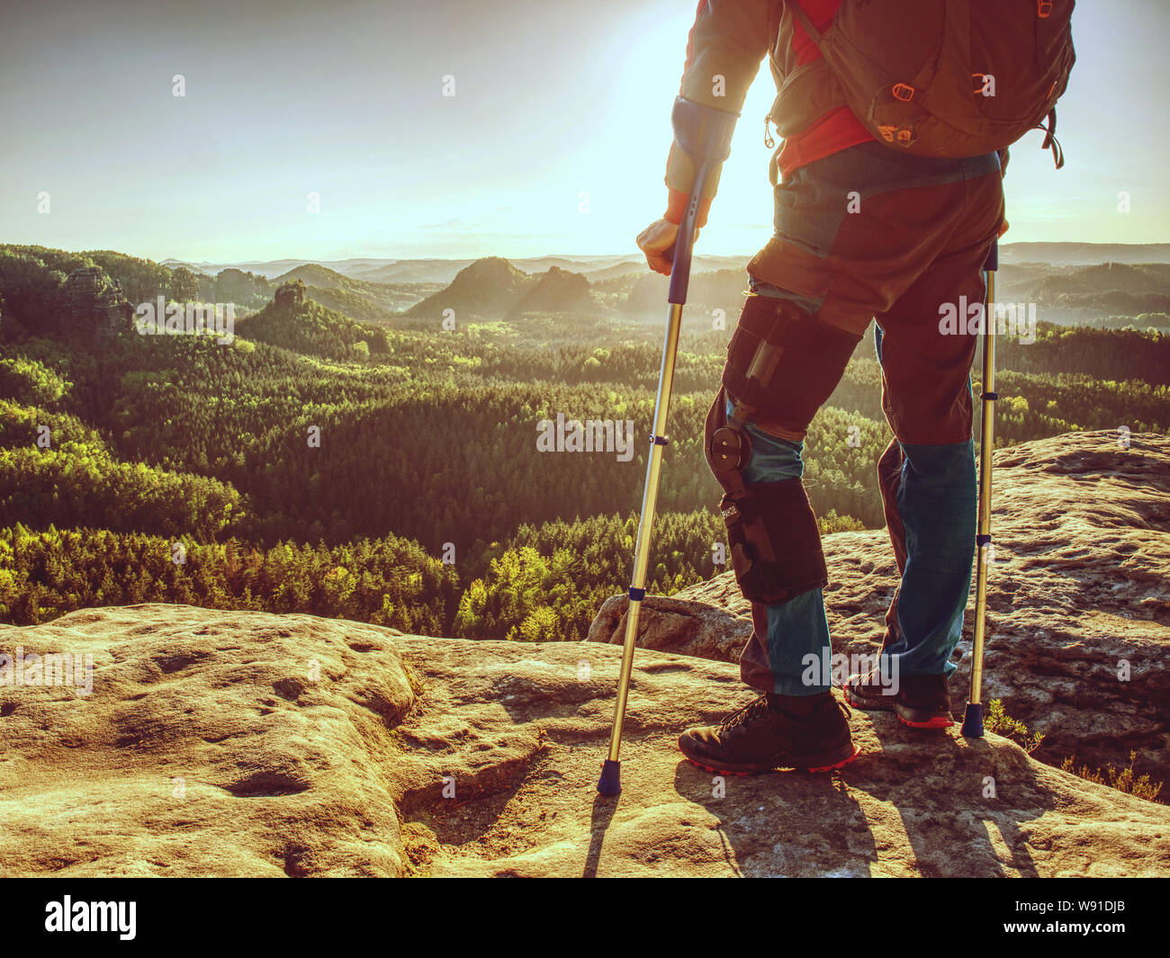 Happy man hiker hold medicine stick, injured knee fixed in knee brace ...