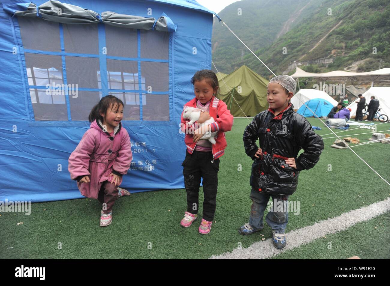 Local children play in front of tents set up at a middle school near ...