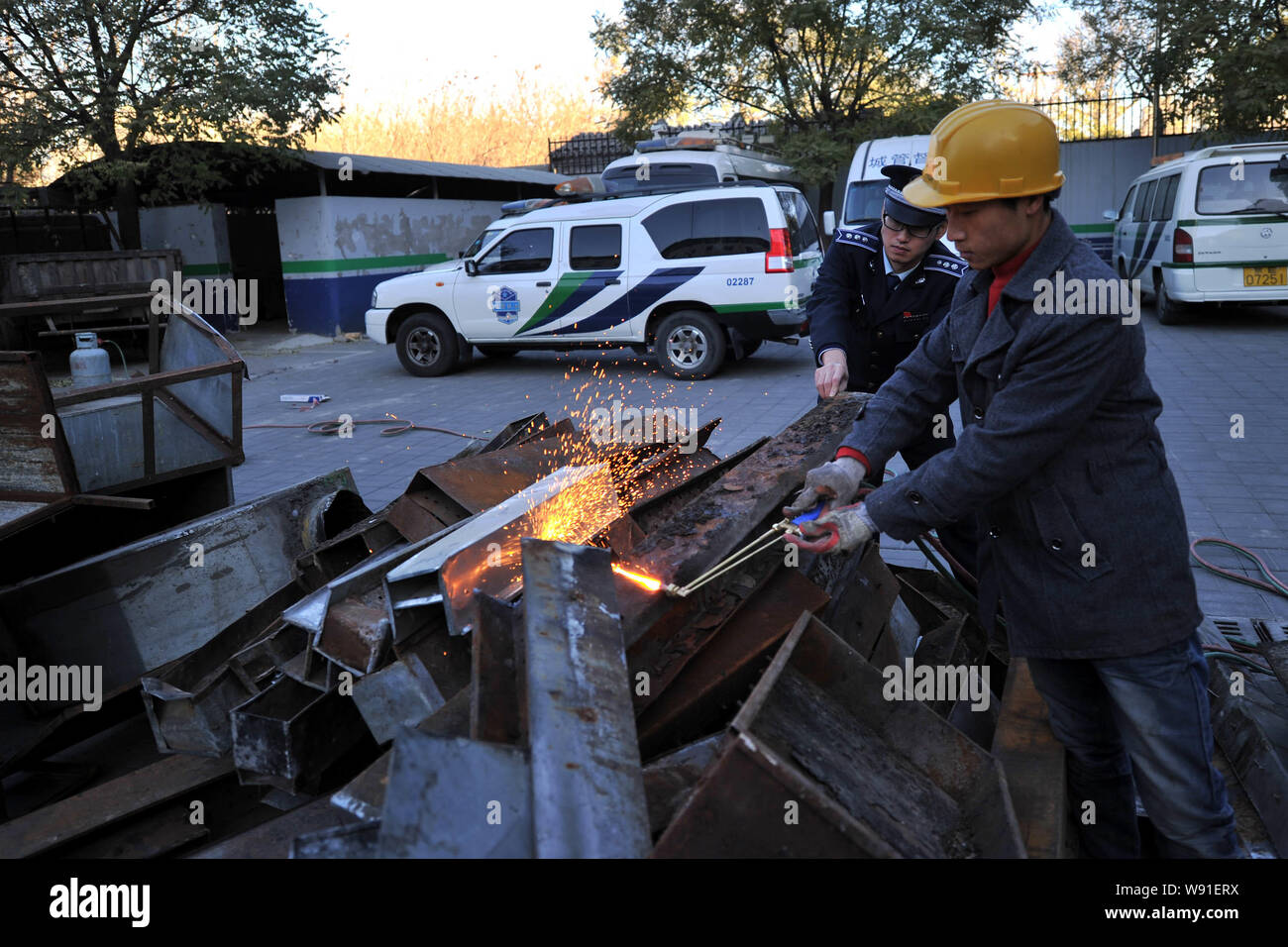 A Chinese worker uses a welding torch to cut apart street barbecue ...