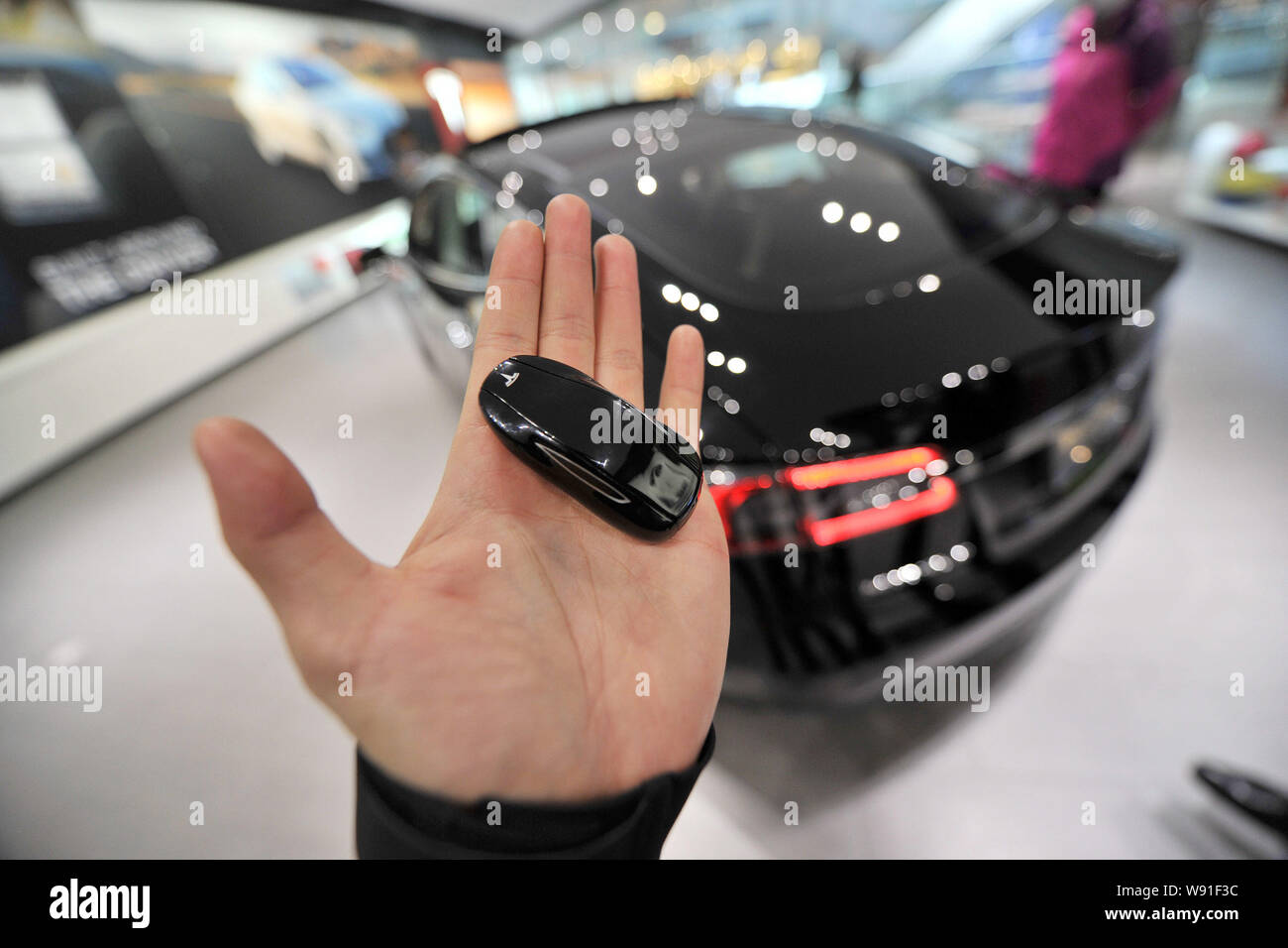 A visitor shows the key of a Model S electric car on display at the ...