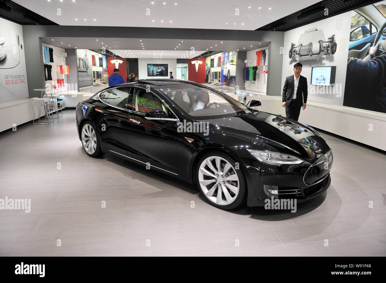 A visitor tries out a Model S electric car on display at the Tesla ...