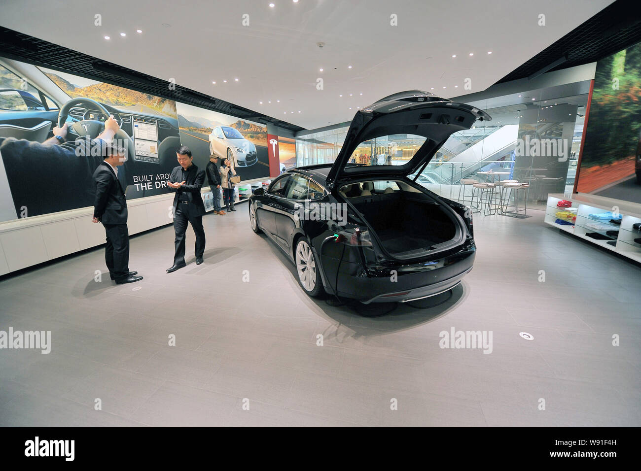 Visitors look at a black Model S electric car on display at the Tesla ...