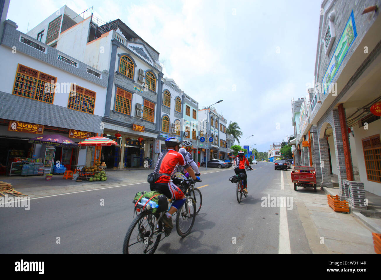 Tourists cycle past refurbished houses along a renovated street in the ...