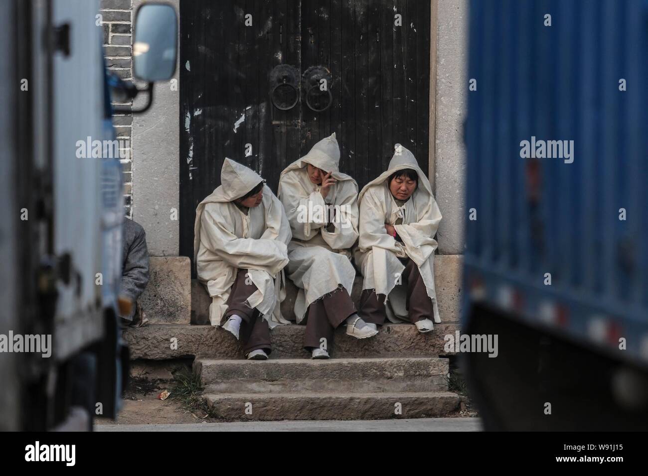 --FILE--Chinese extras dressed in funeral costumes rest during a ...