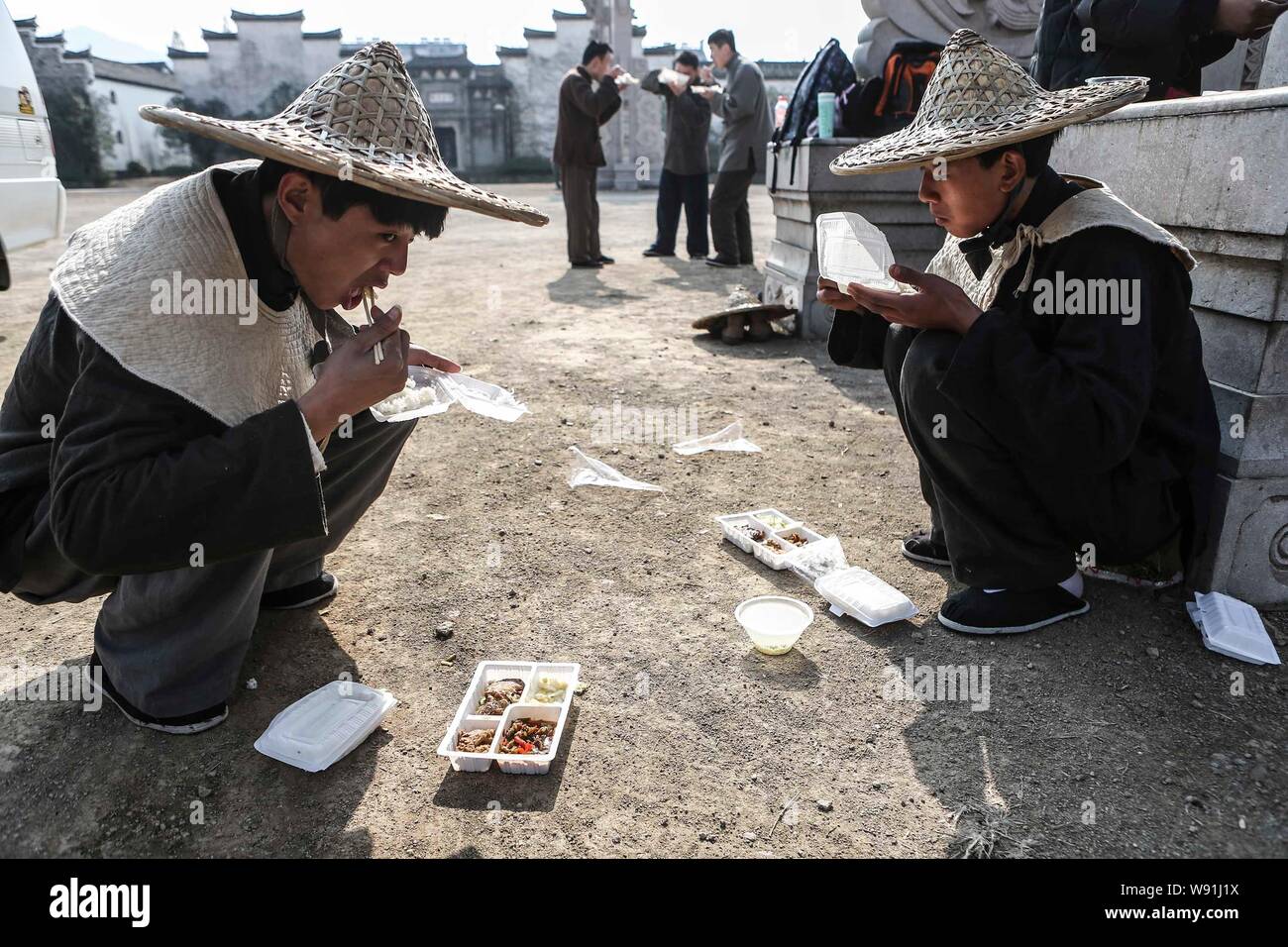 --FILE--Chinese extras eat as they squat on the ground at lunchtime during a filming session of ...