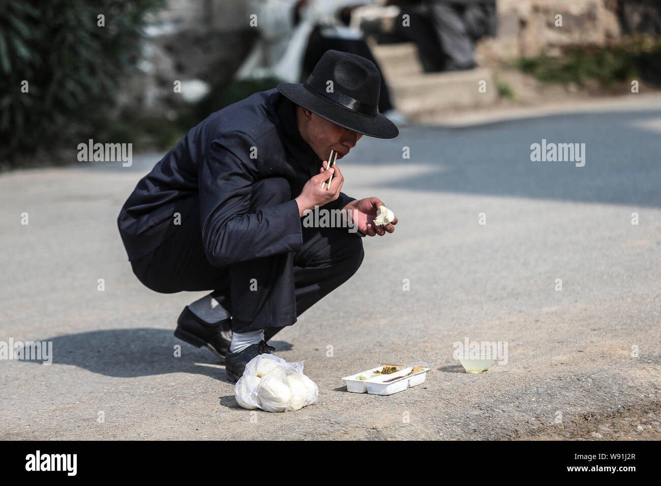 --FILE--A Chinese extra eats as he squats on the ground at lunchtime during a filming session of ...