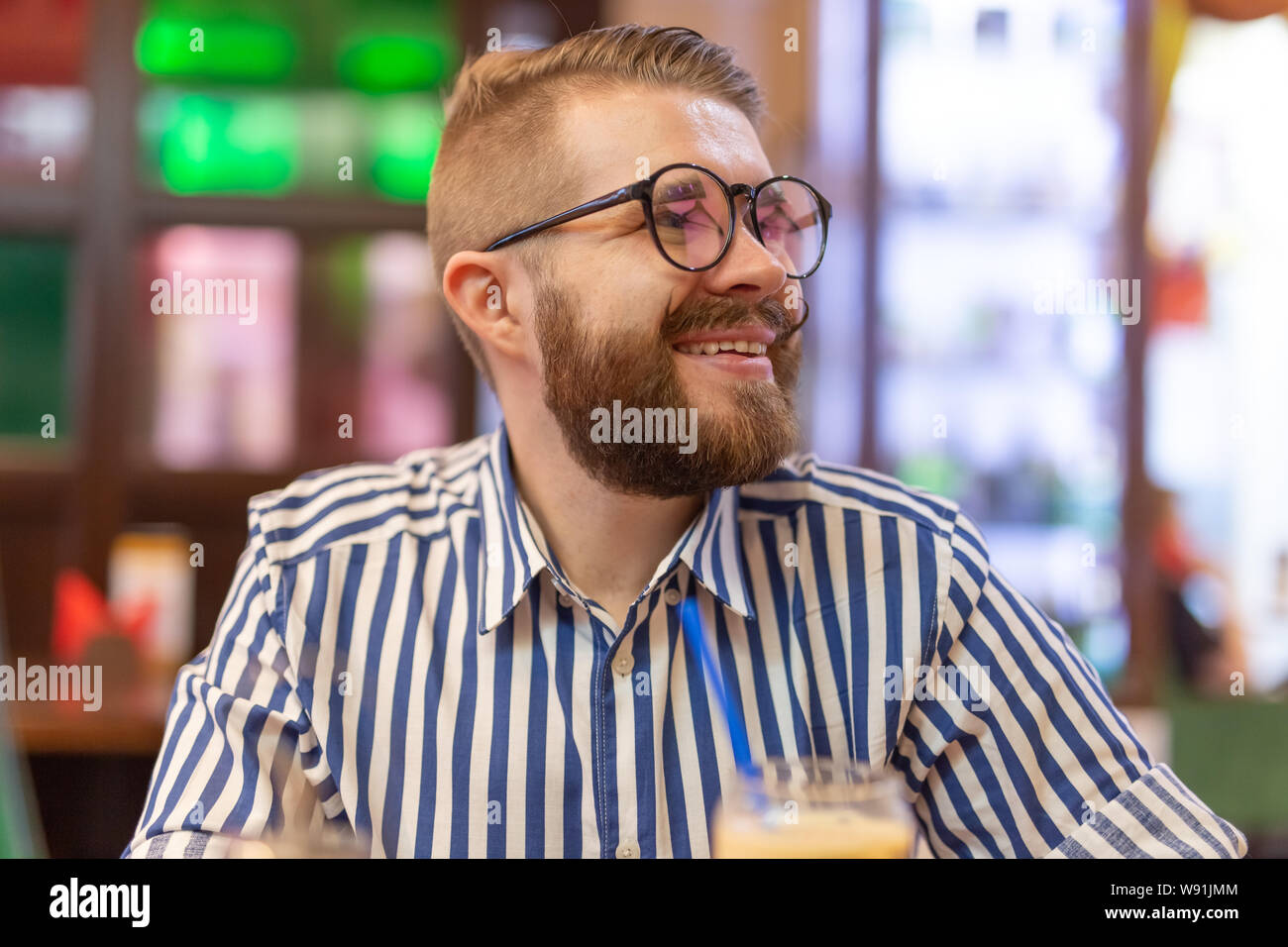 Portrait of a handsome young man with a mustache and beard drinking ice ...
