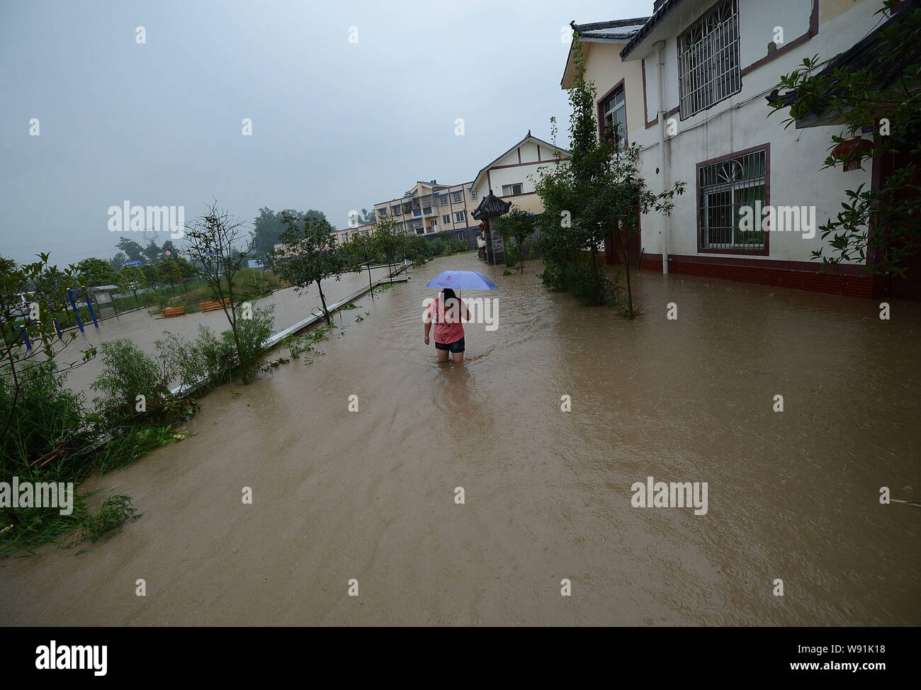 A local resident braves floodwater caused by heavy rain in Guihua town ...