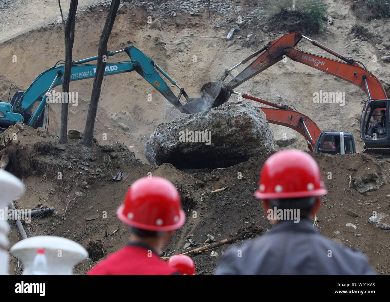 Rescuers operate excavators to clear away a huge rock on the site of a ...