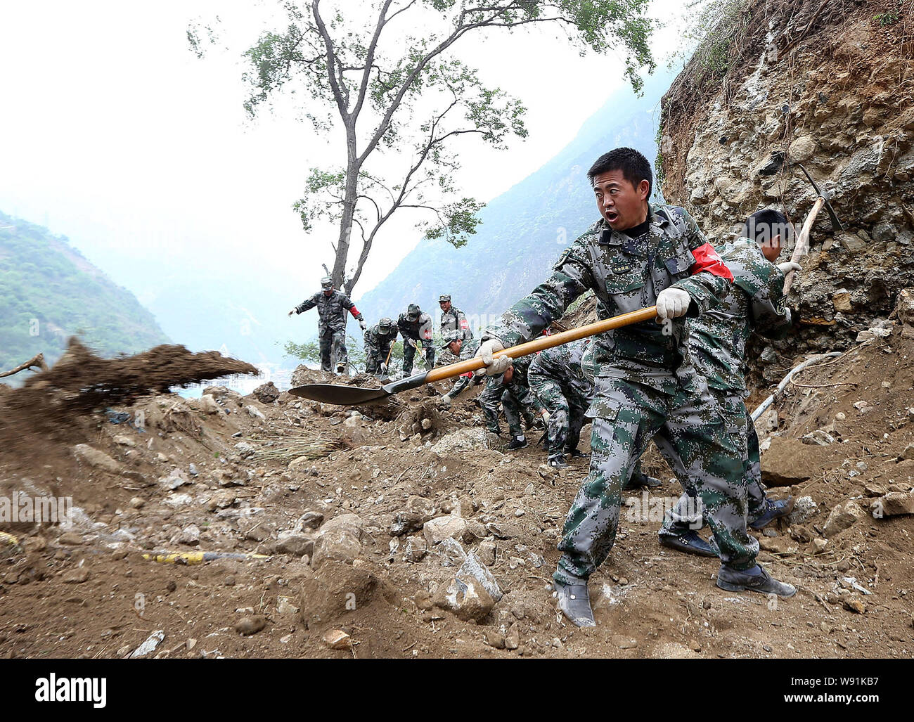 Chinese militiamen clear mud and rocks to make way on the site of a ...
