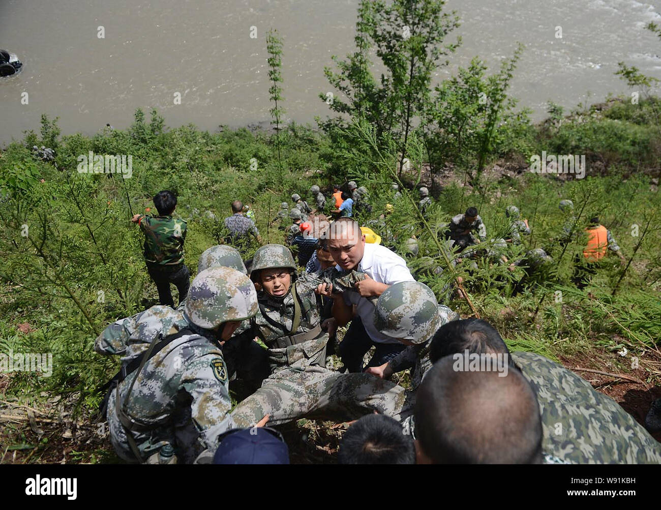 Firemen and local people rescue a soldier who fell into a river with a ...