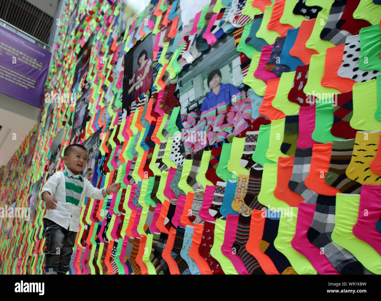 A young boy walks past a dazzling wall decorated with colorful socks ...