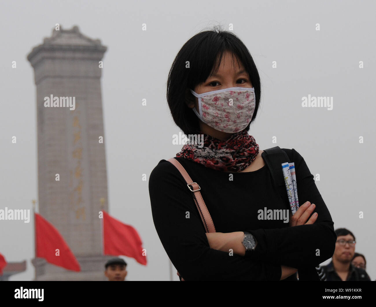 --FILE--A Chinese woman wears a mask is seen in heavy smog in Beijing ...