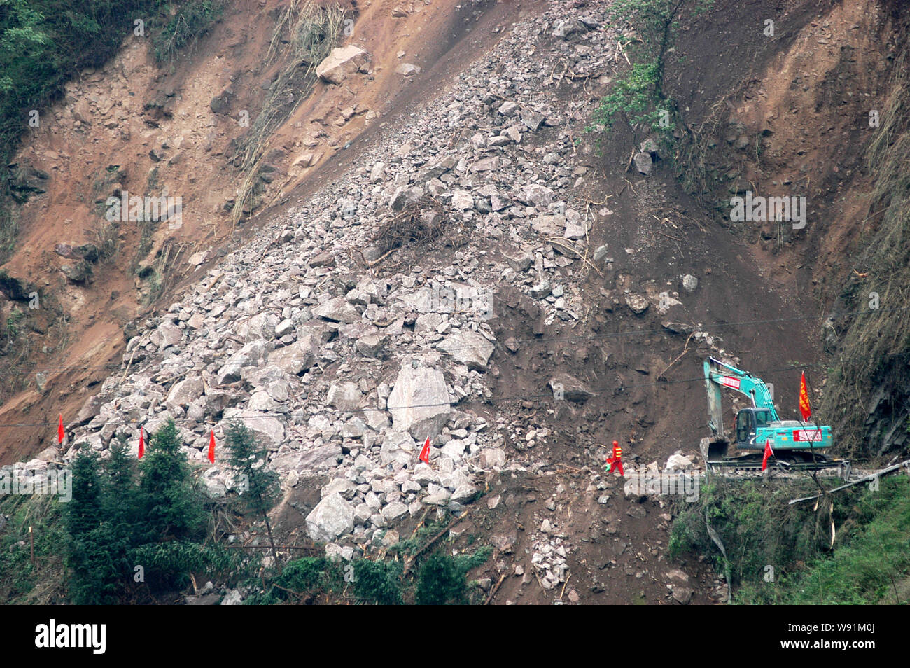A Chinese rescuer looks up at a mountain as he walks through the site ...