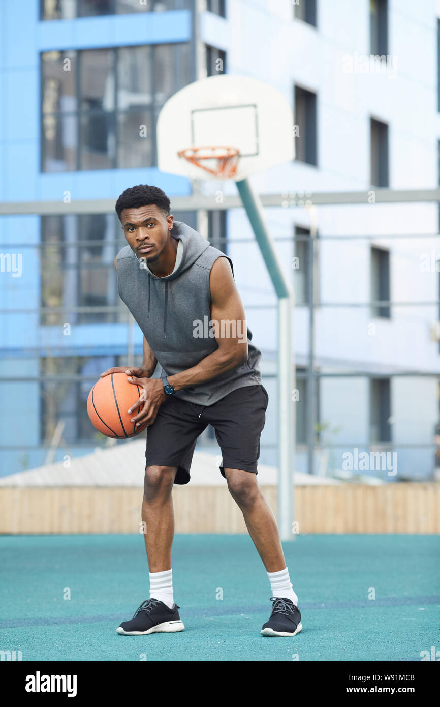 Full length portrait of African basketball player practicing in outdoor ...