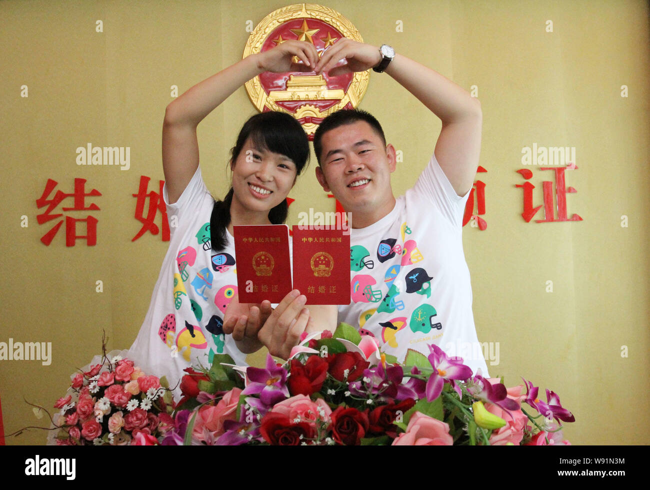 A young Chinese couple poses as they show their marriage certificates ...