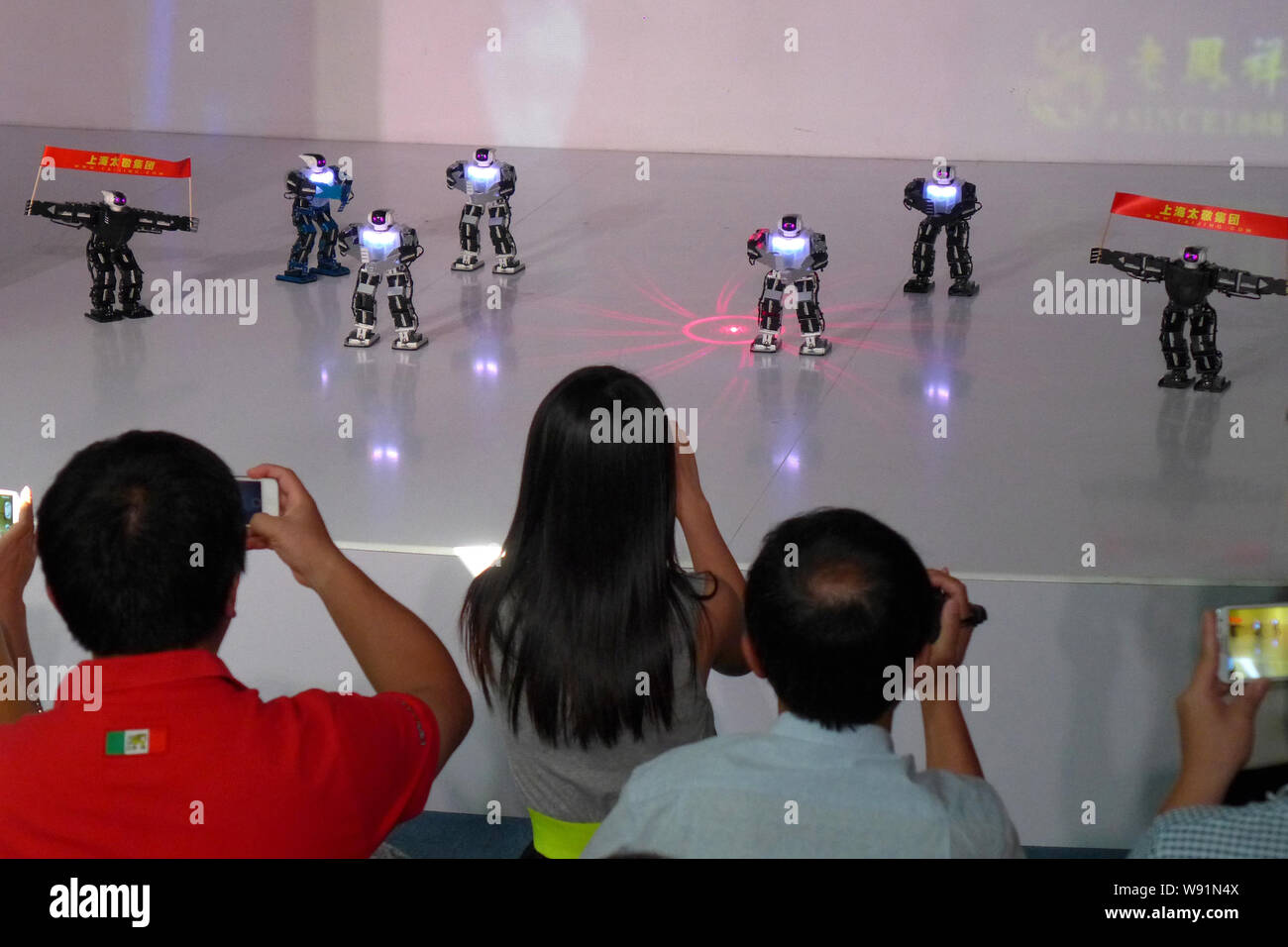 Visitors shoot the performance of robots during the opening ceremony ...