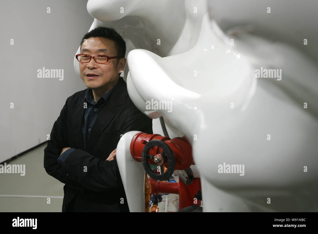 --FILE--Chinese artist Wang Jianwei poses next to one of his artworks at an art exhibition in ...