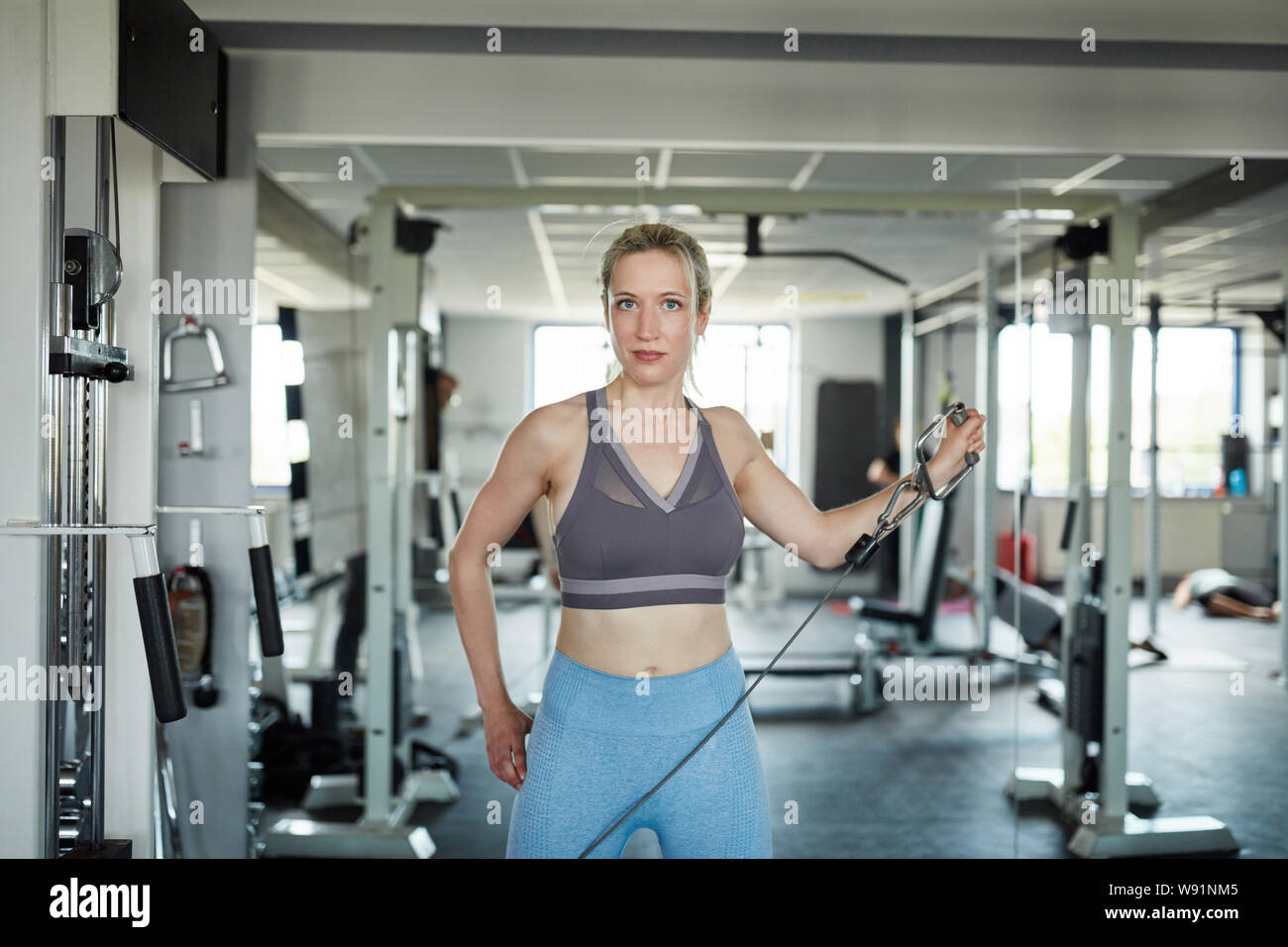 Young woman trains muscle building for triceps on cable in fitness ...