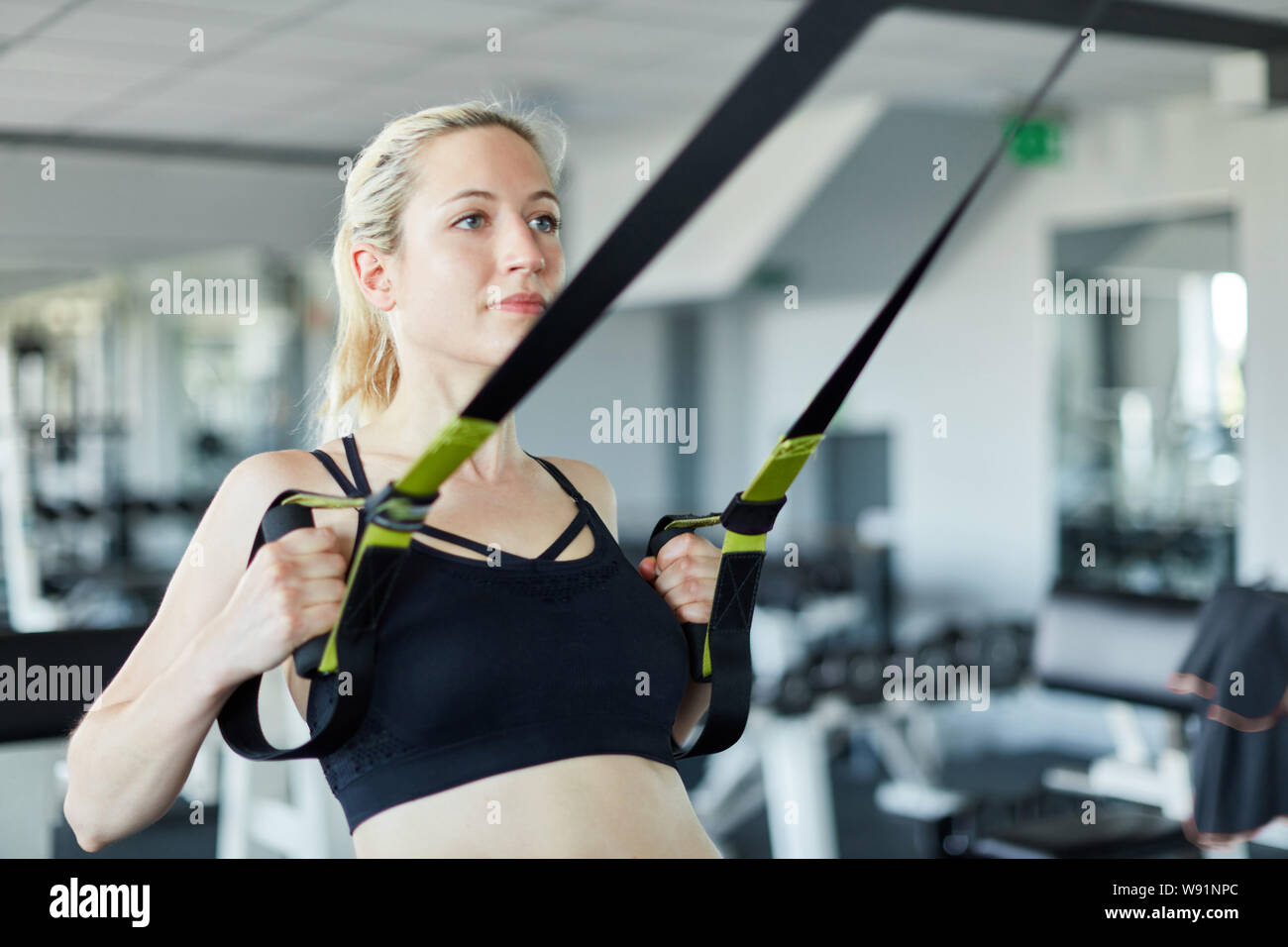 Sporty woman is doing back training with slings at train station in the ...