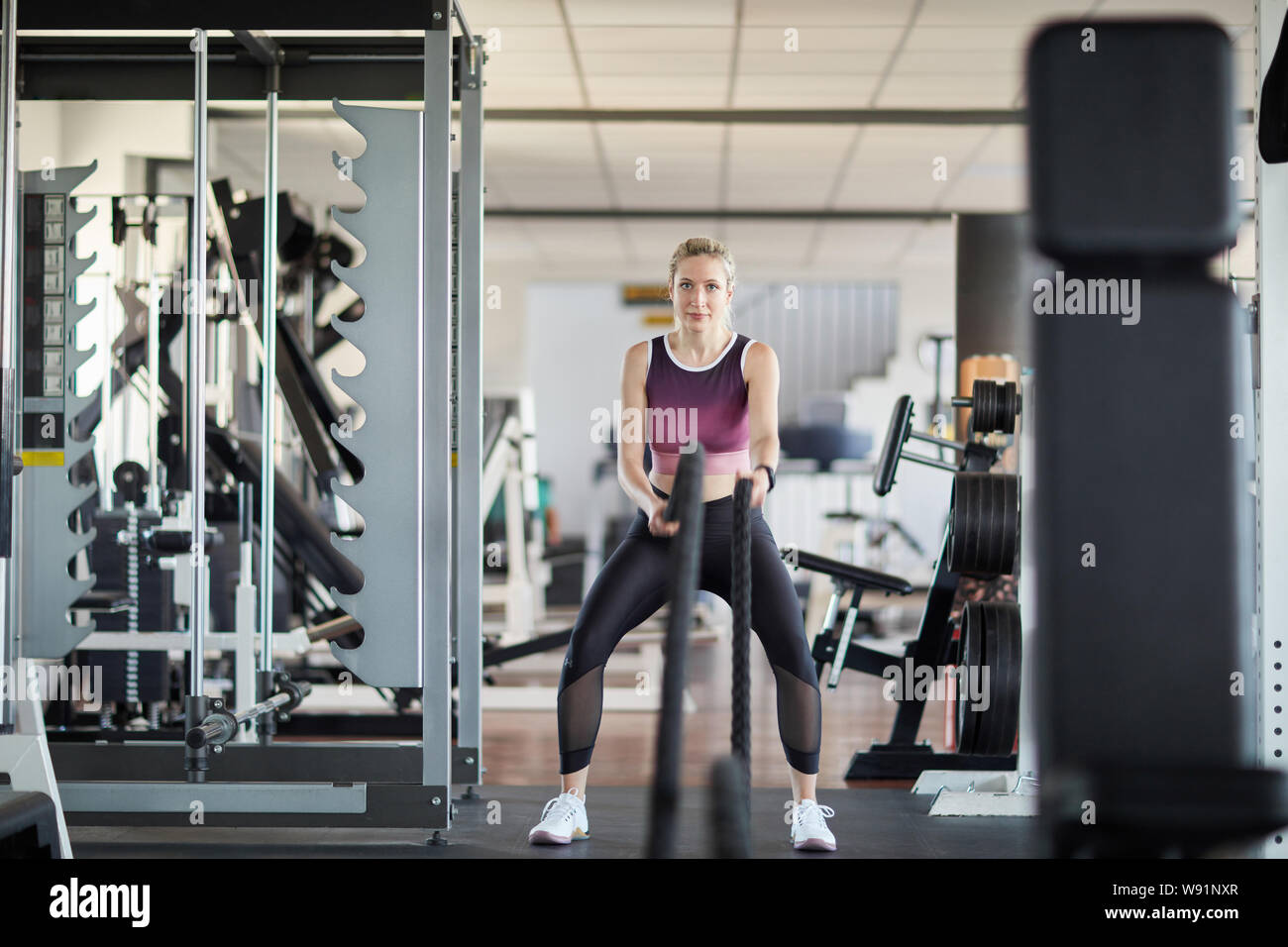 Young woman exercises at Battle Rope in the fitness center Stock Photo ...