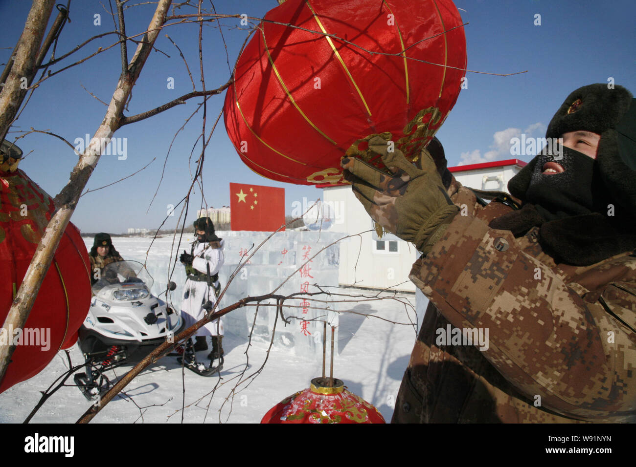 A Chinese PLA (Peoples Liberation Army) soldier hangs up red lanterns ...