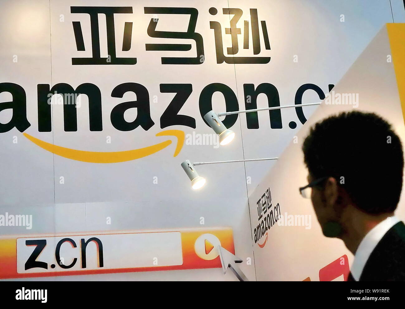 --FILE--A Chinese visitor walks past the stand of Amazon.cn during an ...