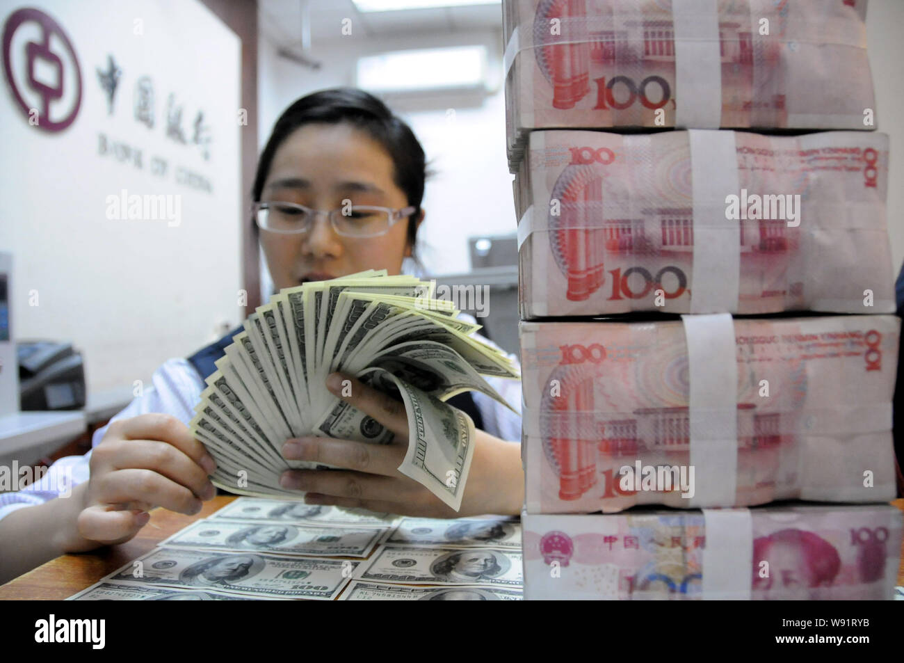 --FILE--A Chinese clerk counts RMB (renminbi) and US dollar bills at a ...