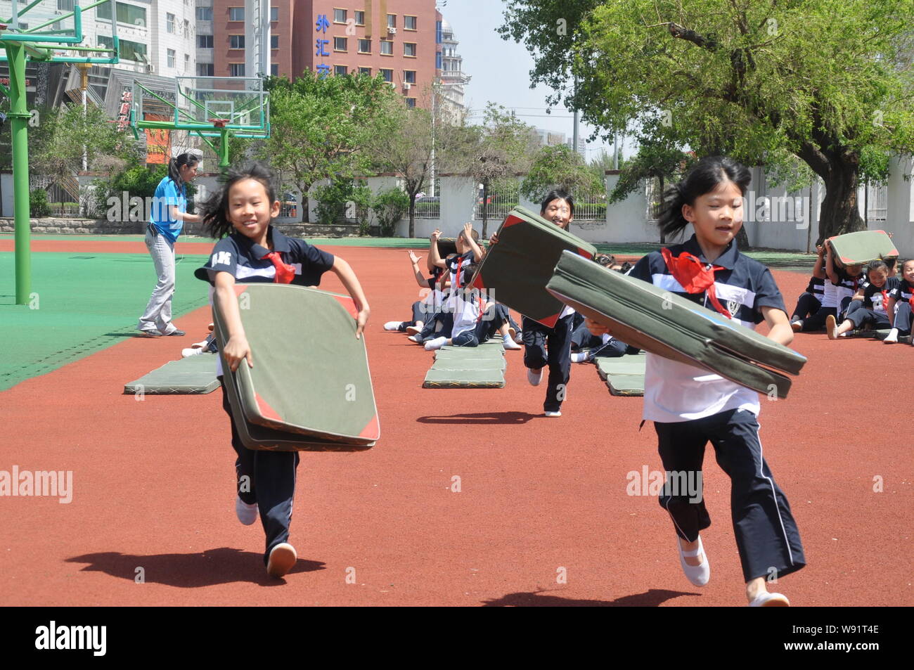--FILE--Students race with gym mats in their hands during a PE lesson ...