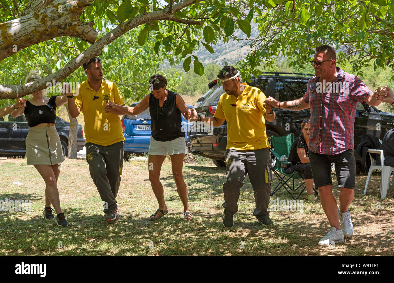 Crete, Greece. Cretans and their guests dance under the shade of Olive ...