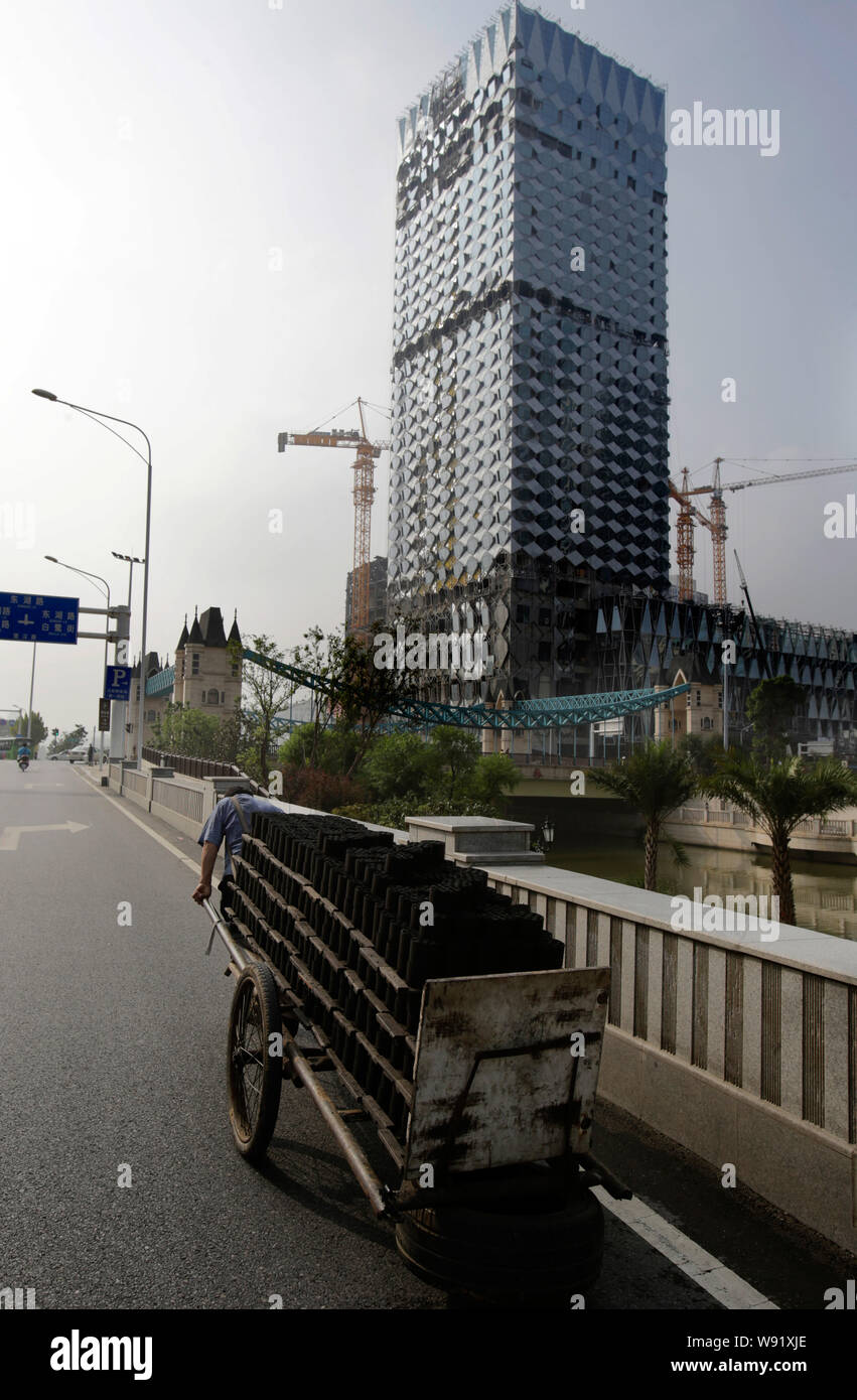 A man pulls a cart loaded with coal past the seven-star hotel, Wanda ...