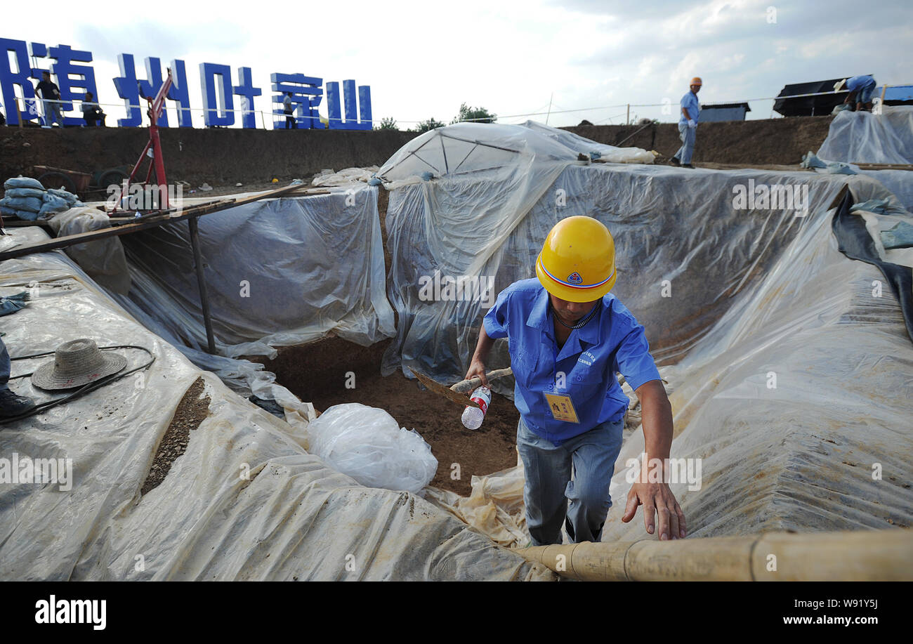 Chinese workers from the local archaeology department cover a ...