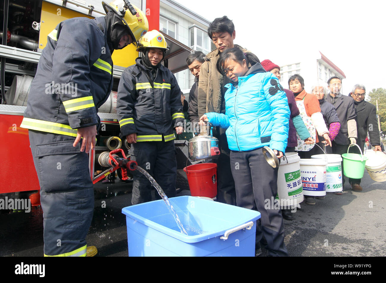 Local Chinese residents carrying buckets queue up next to a fire engine ...