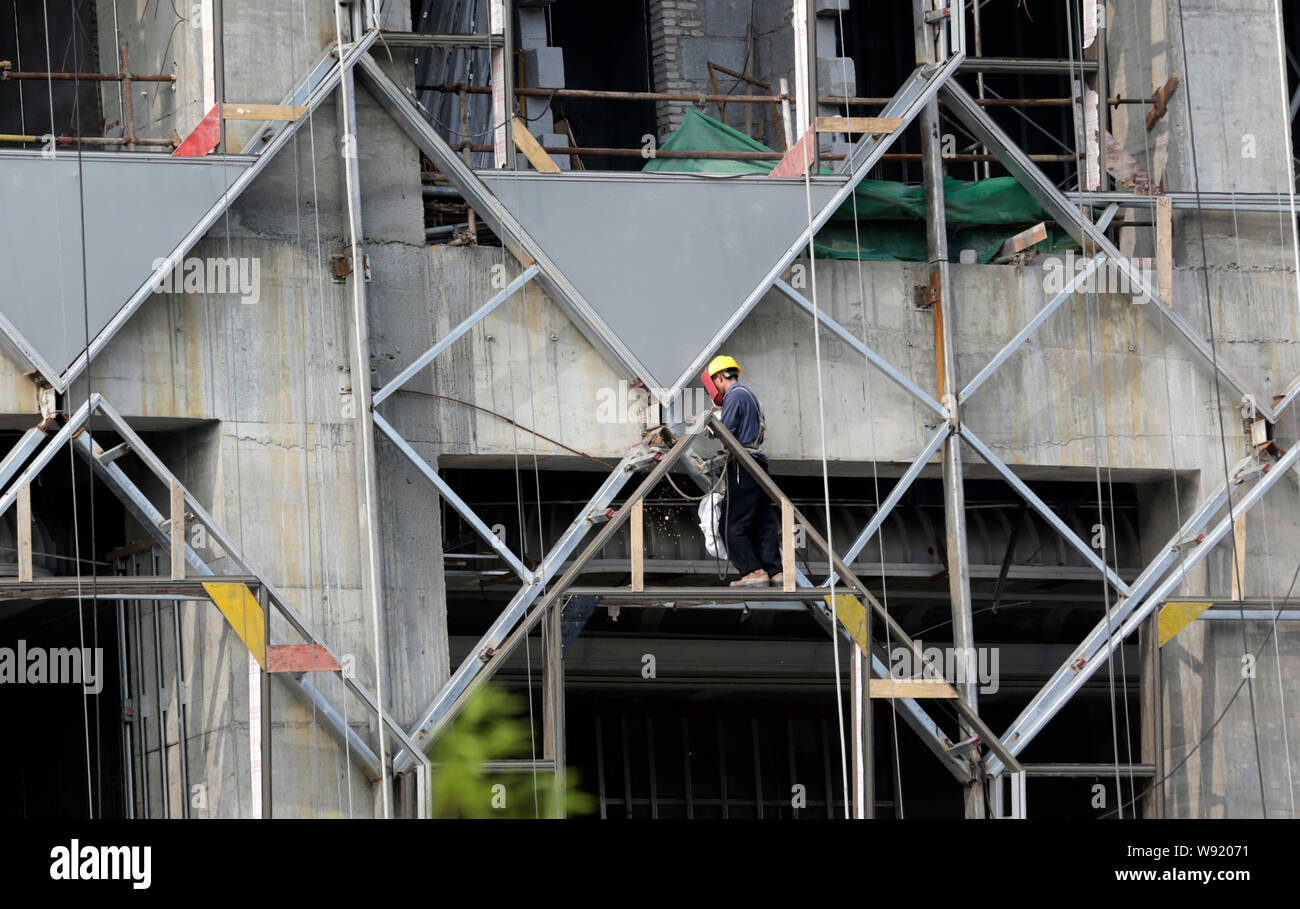 A Chinese worker welds the steel structure on the facade of the seven ...