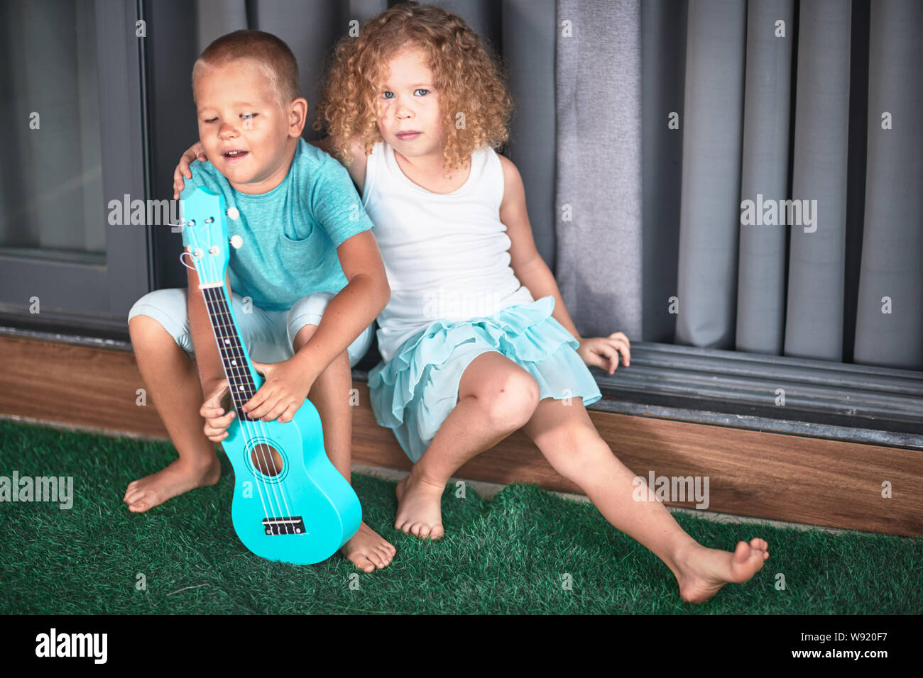 Portrait of a cute kids sitting ouddoor with ukulele Stock Photo - Alamy