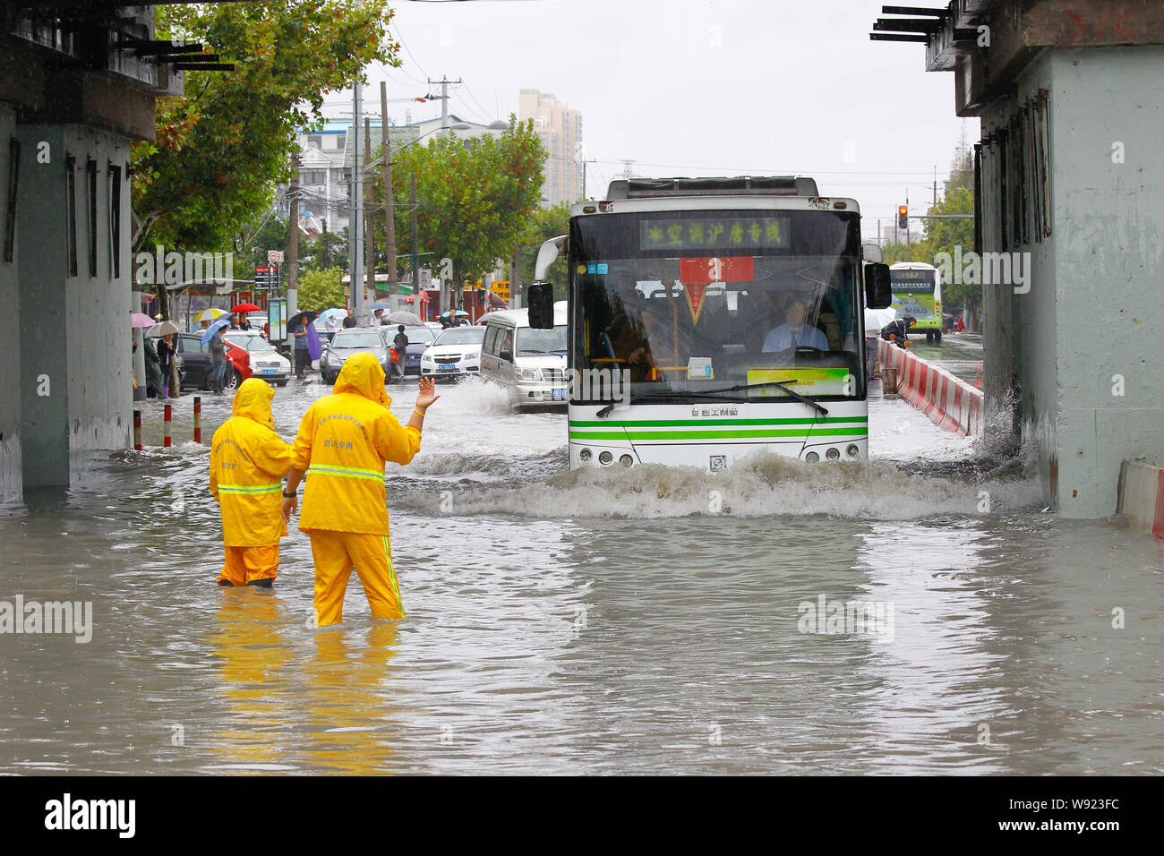 Chinese workers direct a bus on a flooded road in a heavy rain caused ...