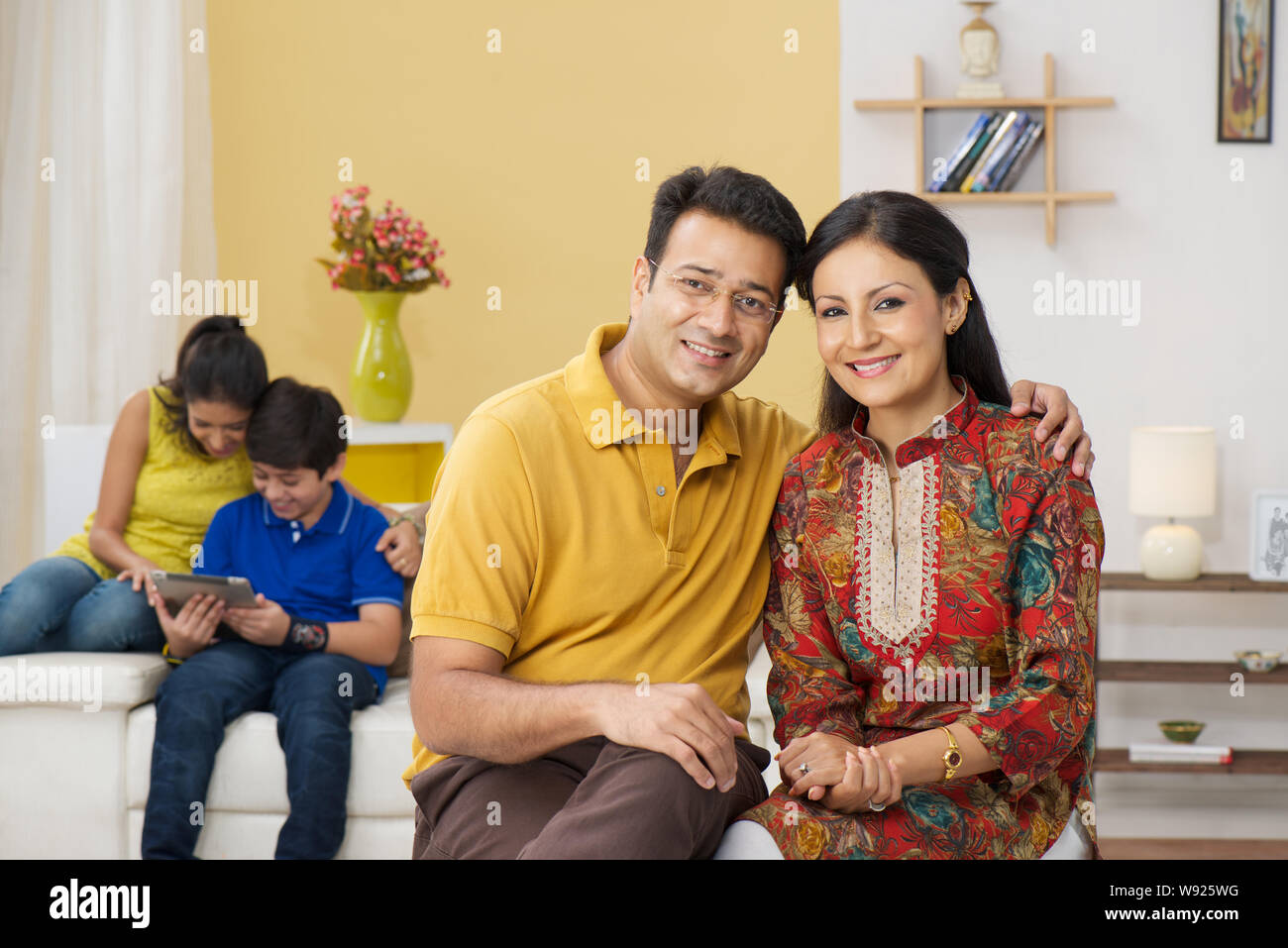 Man with his wife smiling and their children in the background Stock ...